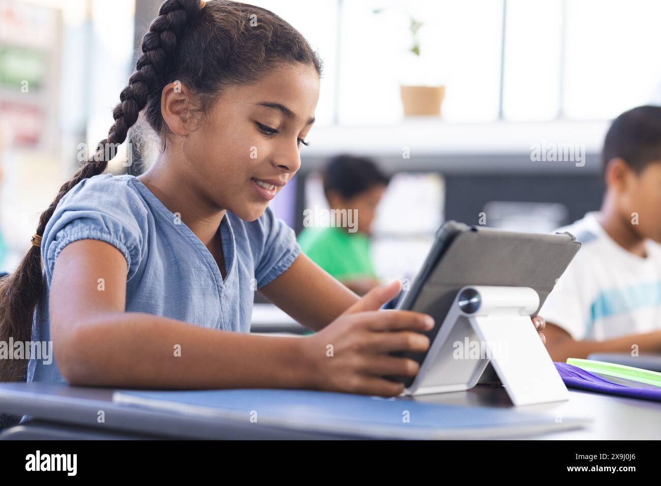 In school, young biracial female student using a tablet in the ...