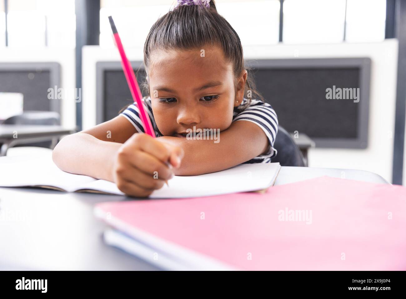 In school, in a classroom, a young biracial girl with light brown skin ...