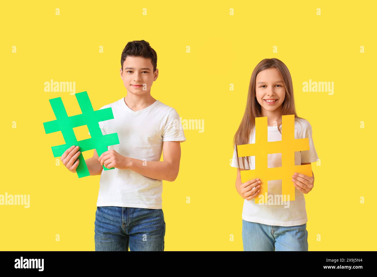 Cute teenage kids with hashtags on yellow background Stock Photo - Alamy