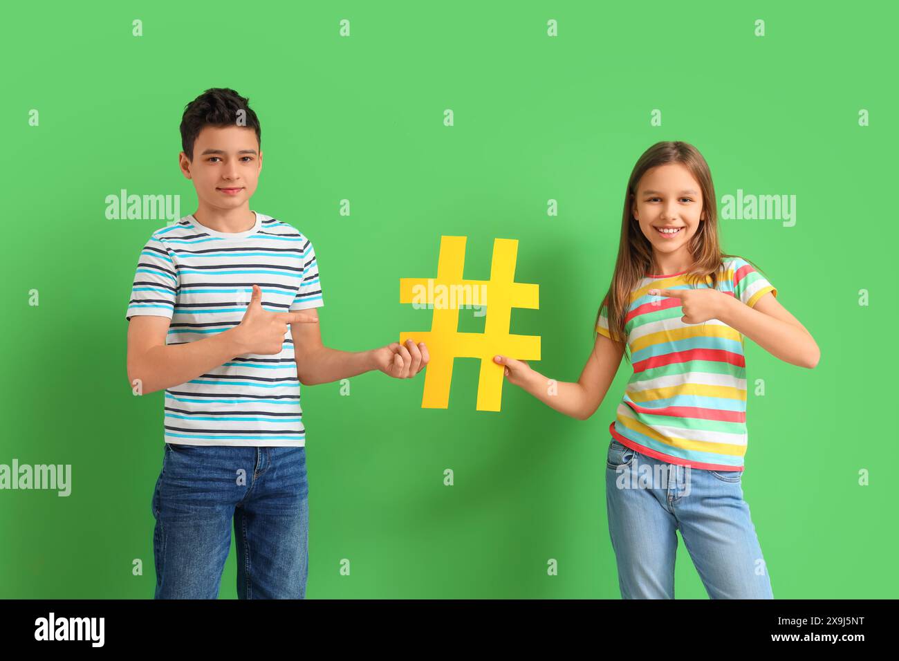 Cute teenage kids pointing at hashtag on green background Stock Photo ...