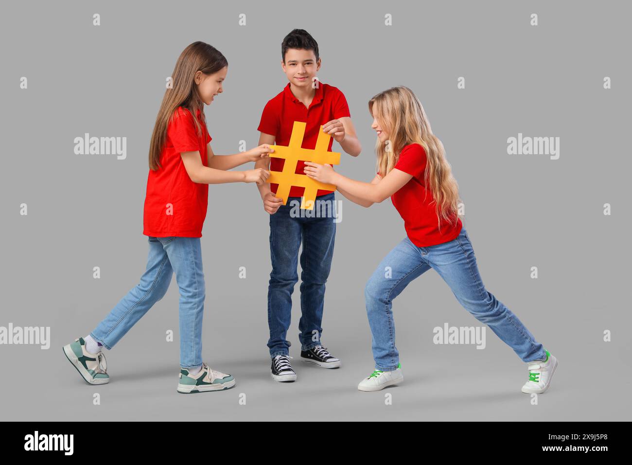 Cute kids fighting over hashtag on grey background Stock Photo - Alamy