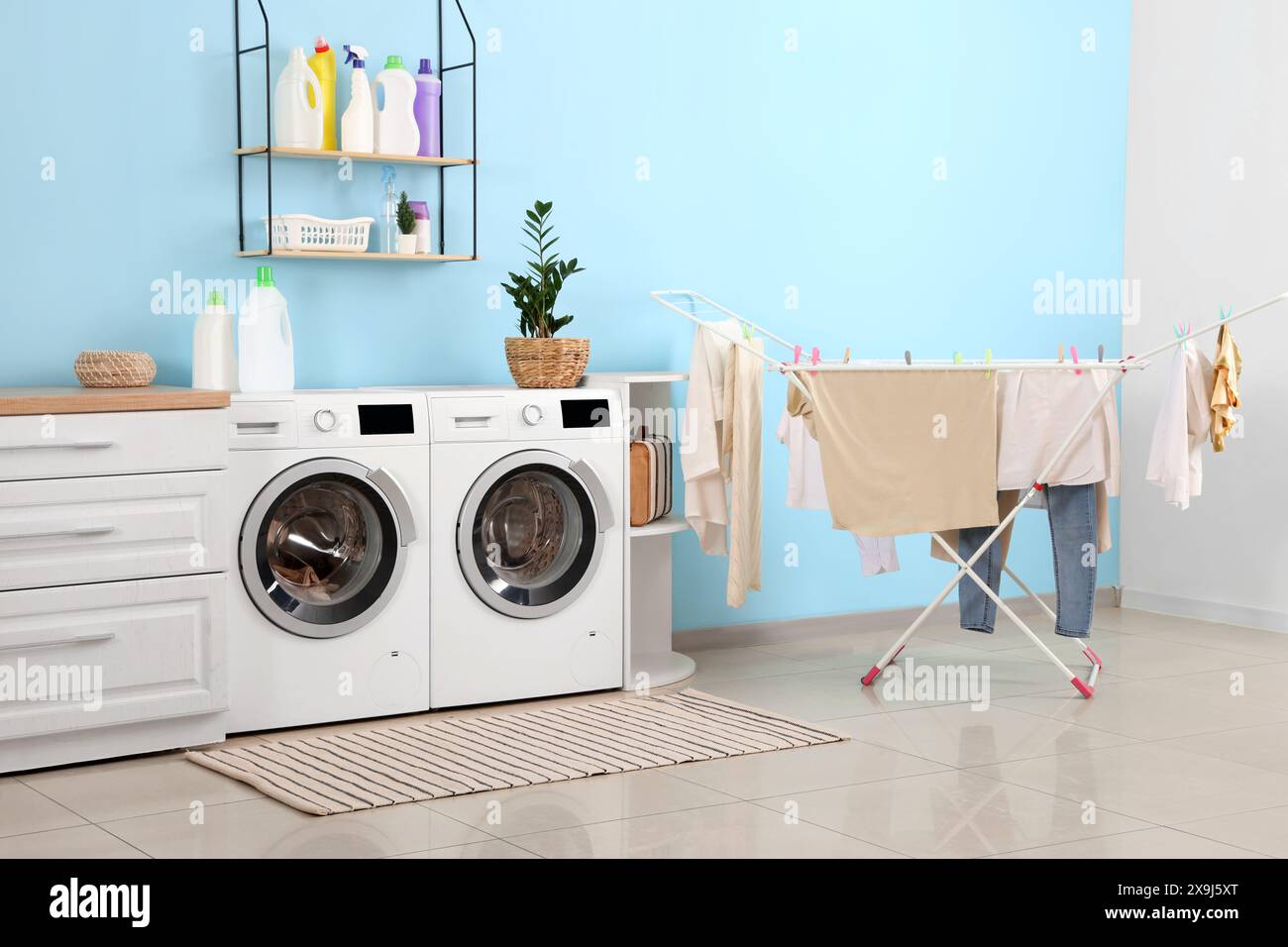 Interior of modern laundry room with washing machines and clean clothes ...