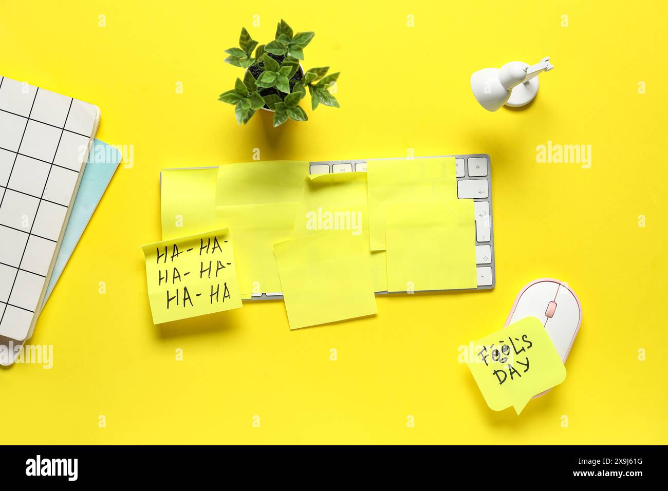 Computer keyboard taped with sticky notes on yellow background. April ...