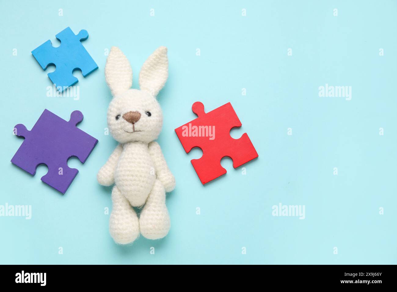 Colorful puzzle pieces and toy bunny on blue background. Concept of ...