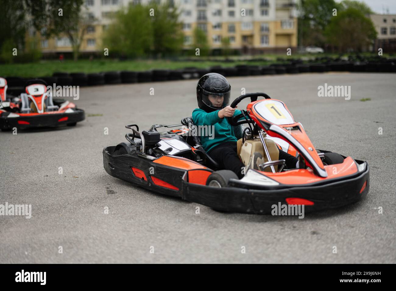 Kid in a black helmet driving a go-kart during an intense race ...