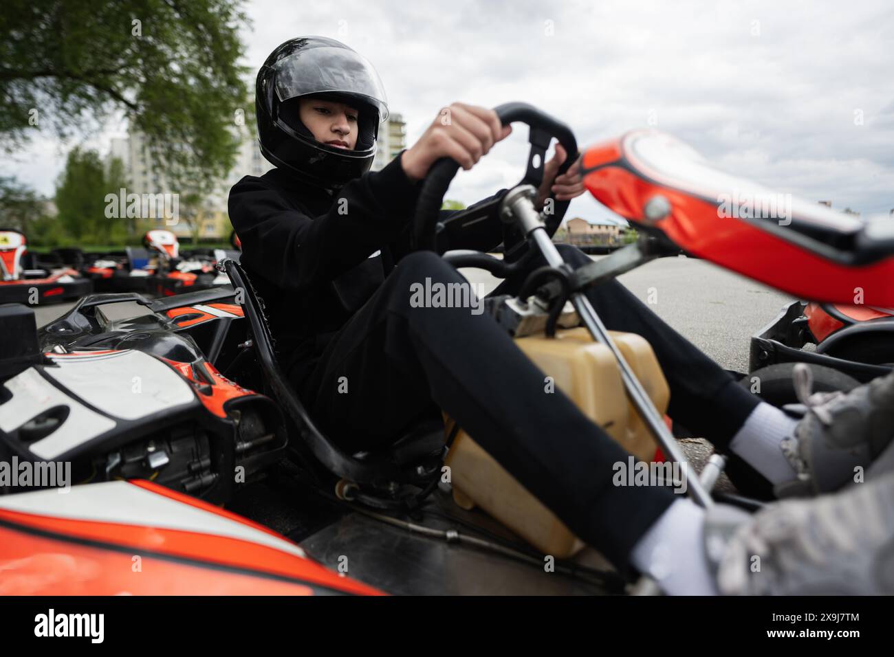 Close-up of a focused person in a black helmet driving a go-kart during ...