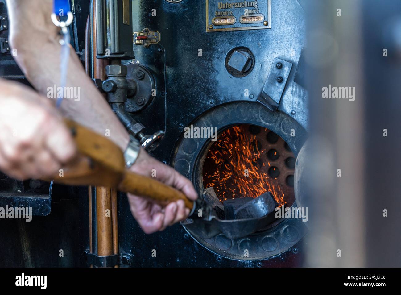 01 June 2024, Brandenburg, Cottbus: Coal is shoveled into the furnace ...