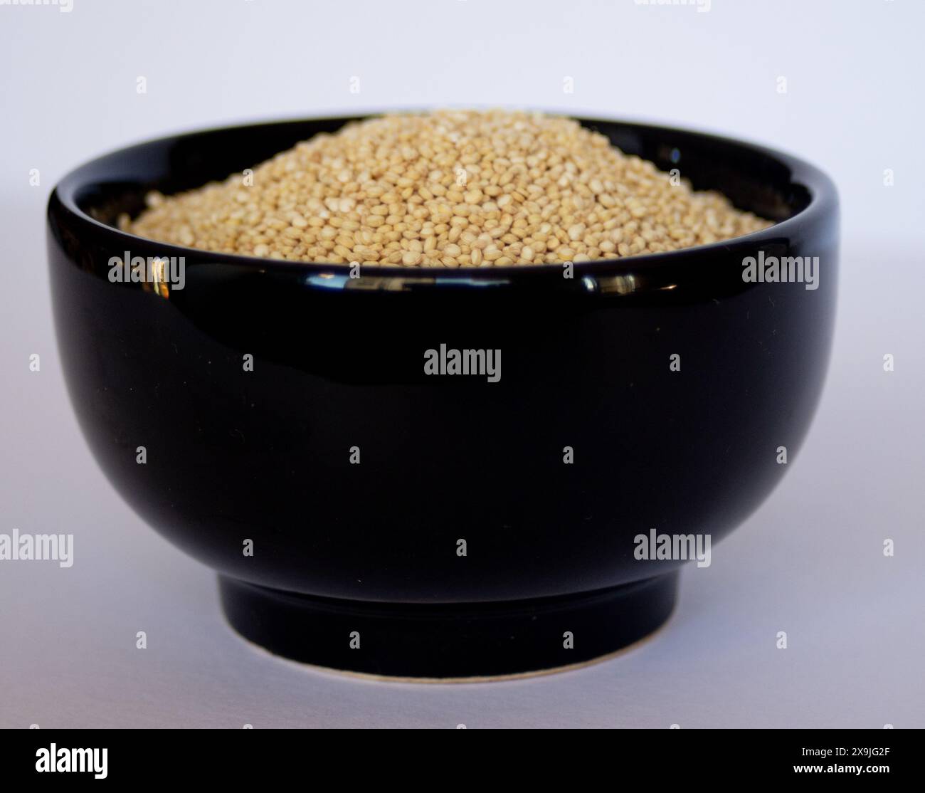 Quinoa grains in black bowl. side view picture in white background ...