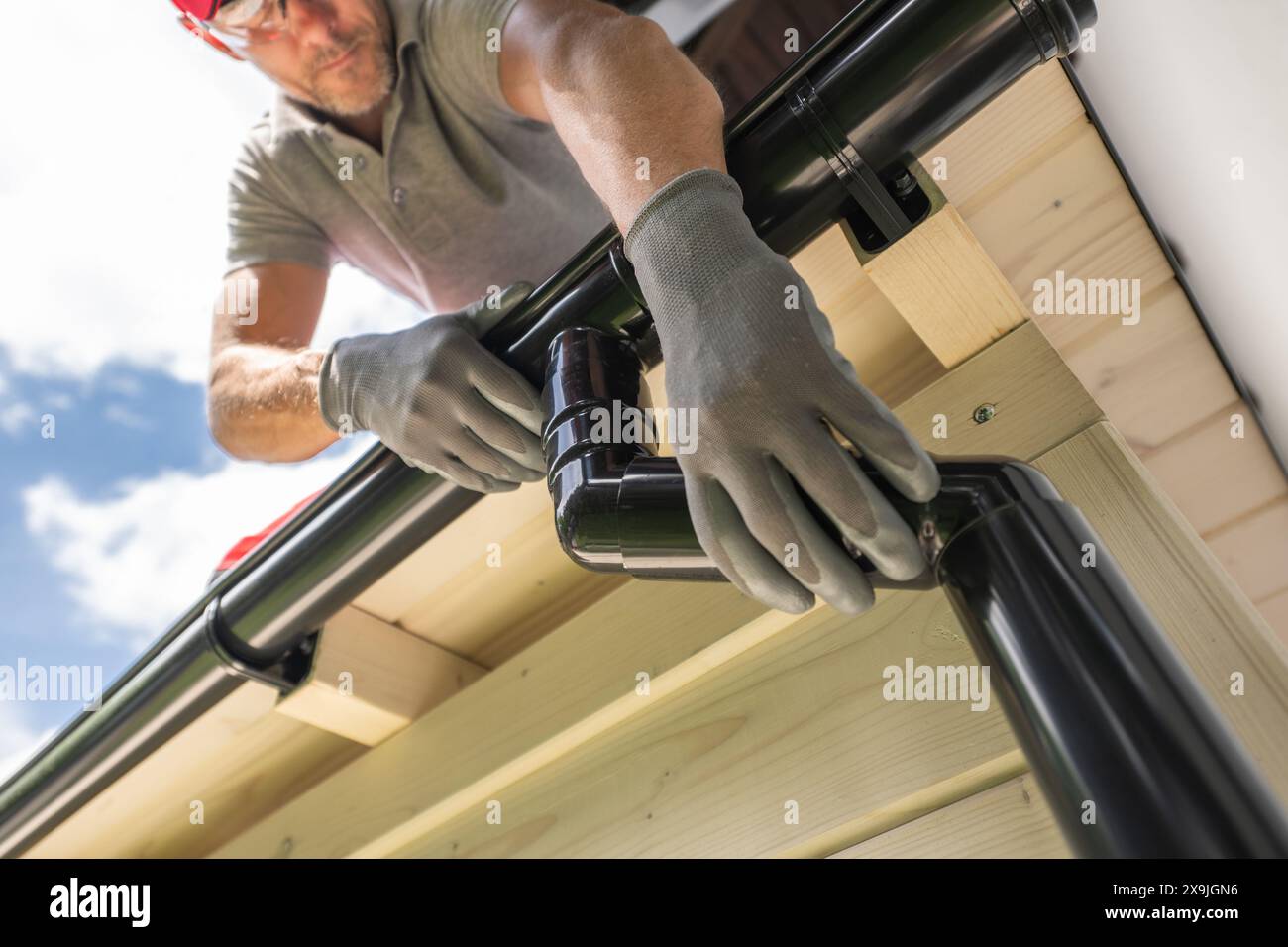 Worker Installing Gutter System on Roof Stock Photo - Alamy