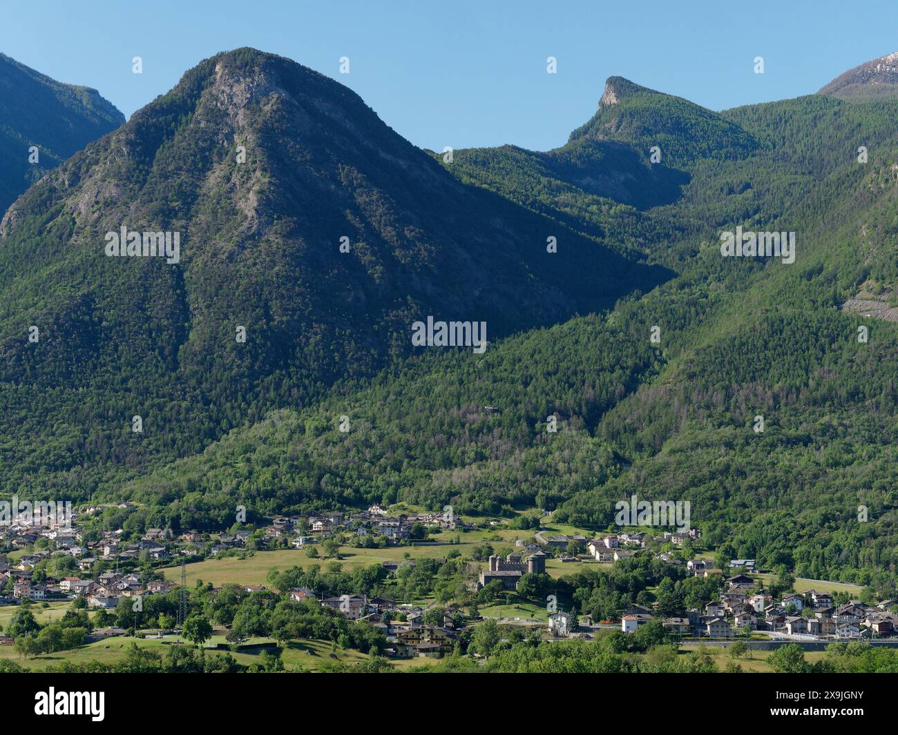 Town of Fenis and its castle beneath towering mountains in the Aosta ...