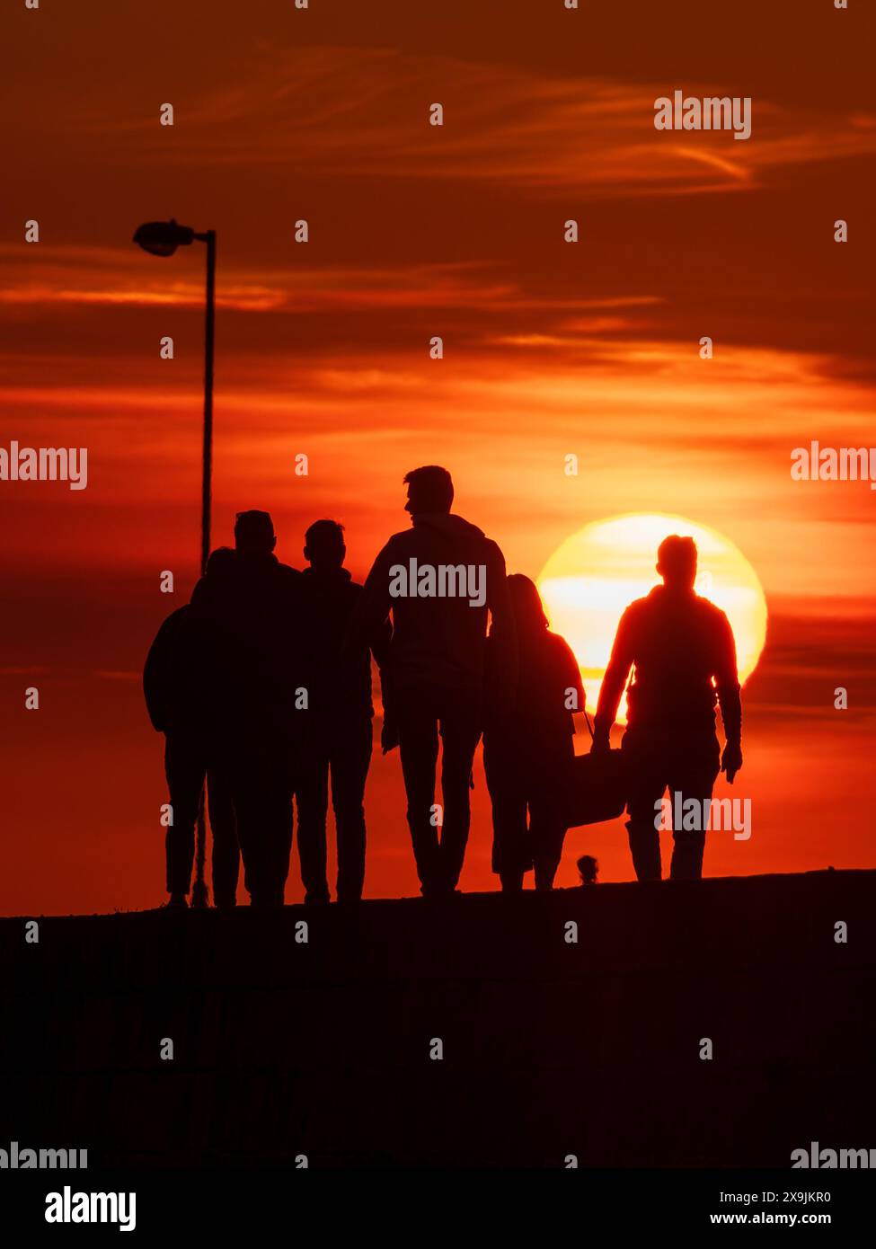 Sunset silhouettes on the Howth pier Stock Photo - Alamy