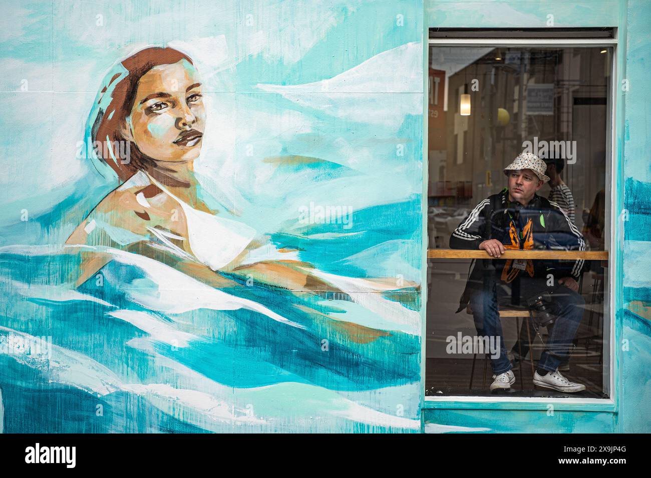 A person in sits in a coffee shop beside a new graffiti artwork at the ...