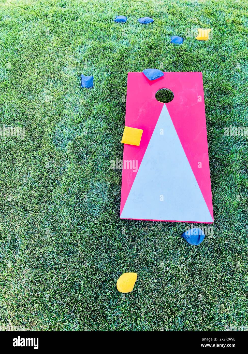 Red cornhole board lawn game leisure activity with bean bags on grass ...