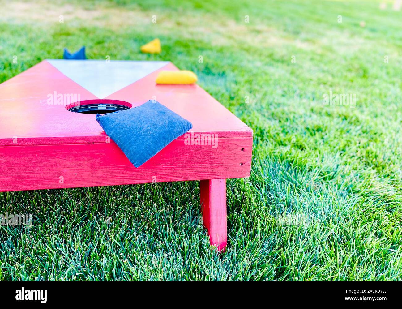 Red cornhole board lawn game leisure activity with bean bags on grass ...