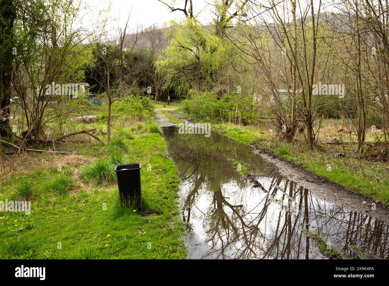 A muddy gravel road going into a rural mobile home community hollow ...