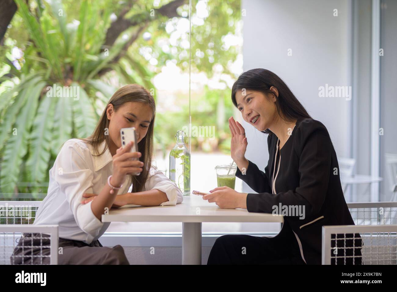 Two Asian women having a pleasant conversation over coffee in a modern ...