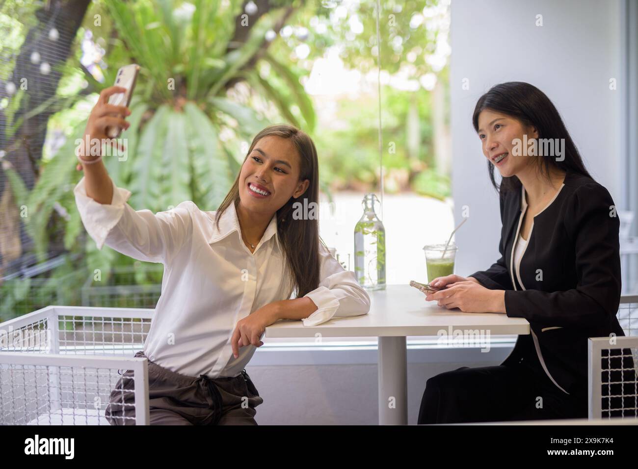 Two Asian women having a pleasant conversation over coffee in a modern ...