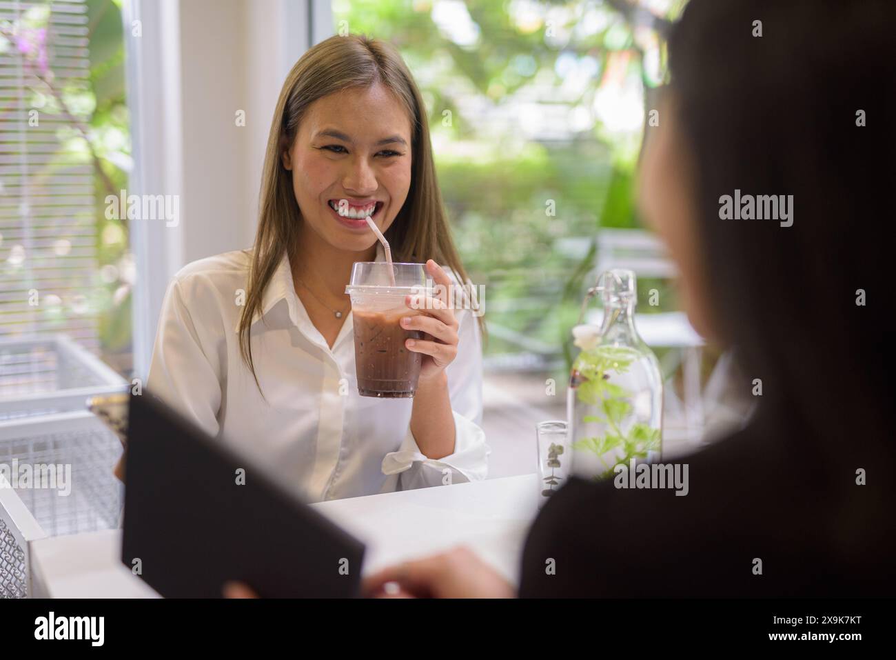 Two Asian women having a pleasant conversation over coffee in a modern ...