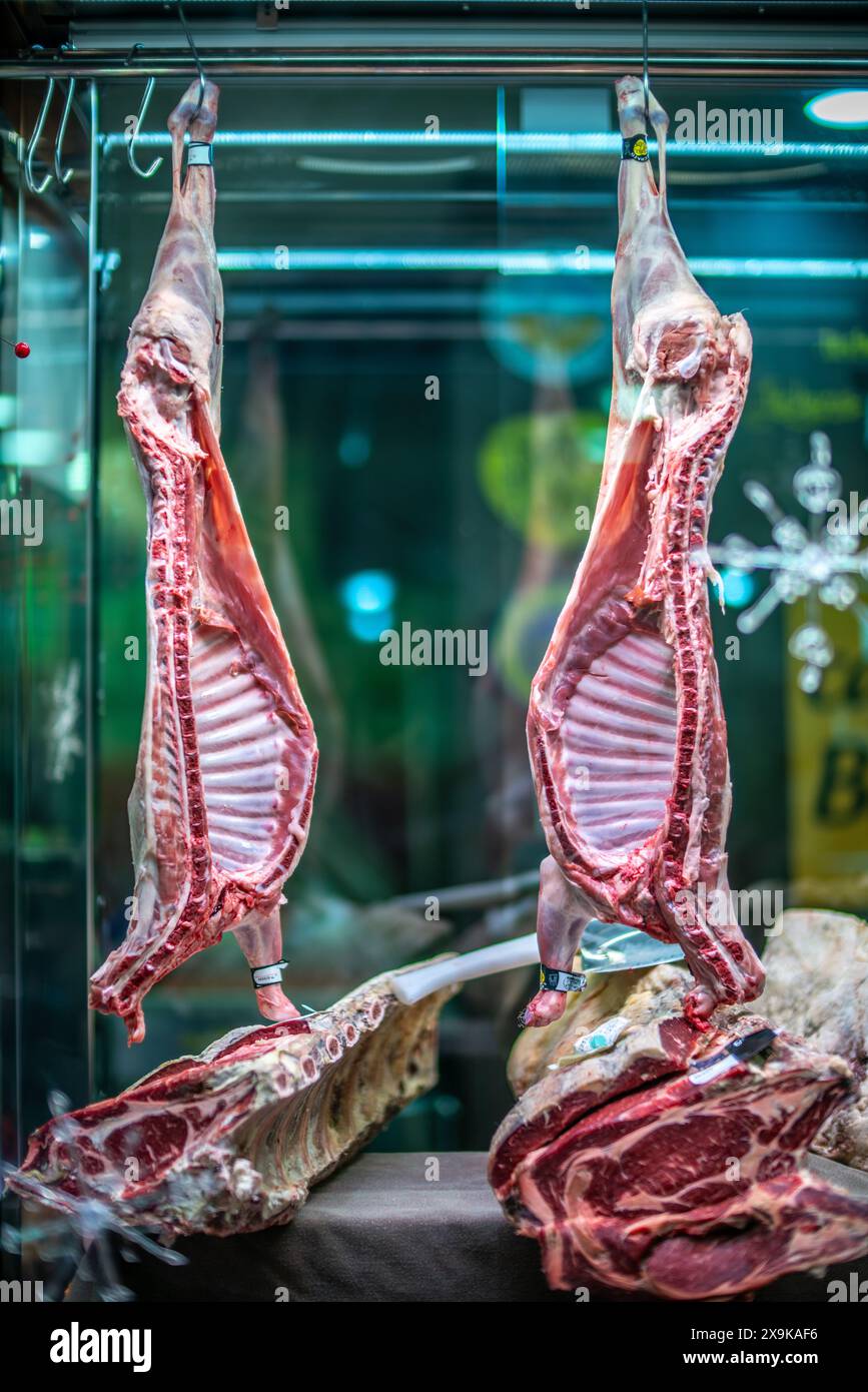 Two lamb carcasses and a beef rib hang in a Seville butcher shop ...