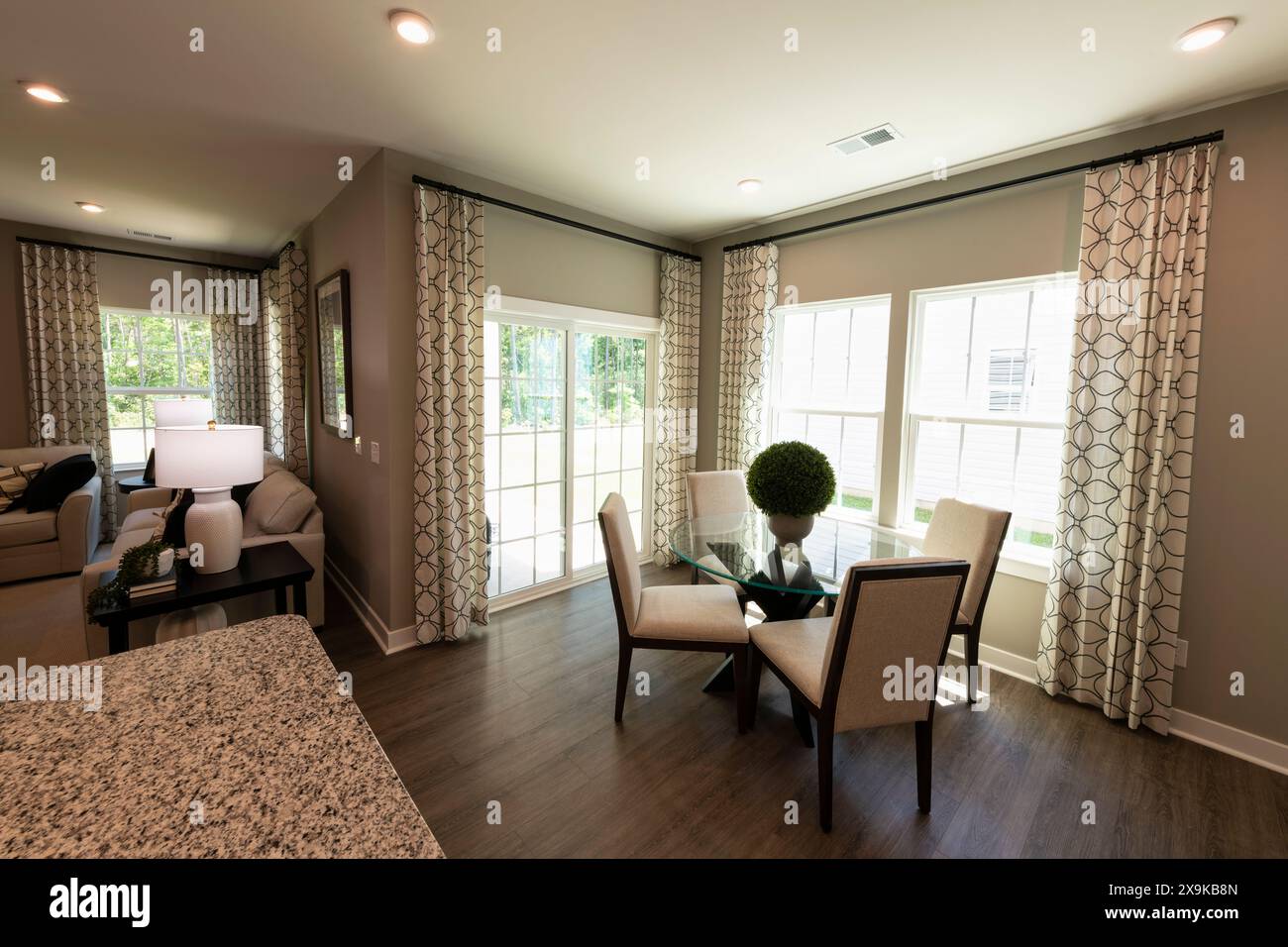 Sunny dining room with large windows, wooden upholstered chairs, floral ...