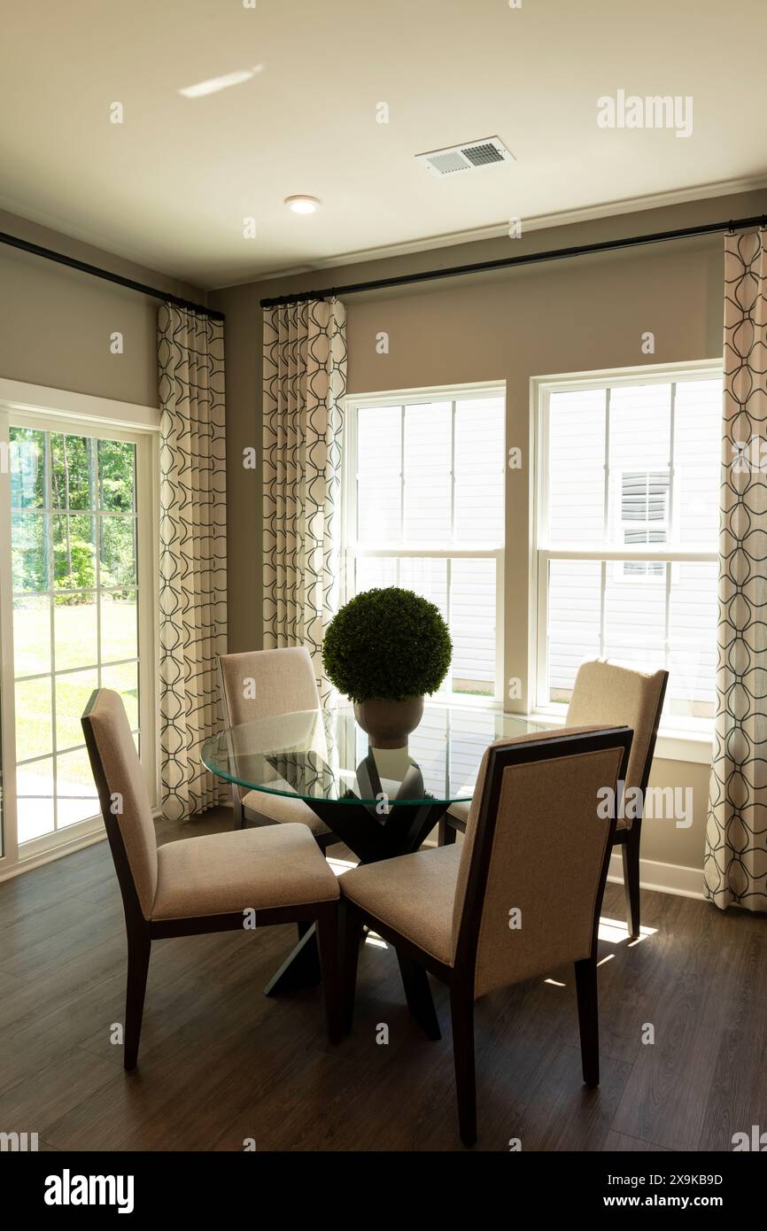 Sunny dining room with large windows, wooden upholstered chairs, floral ...