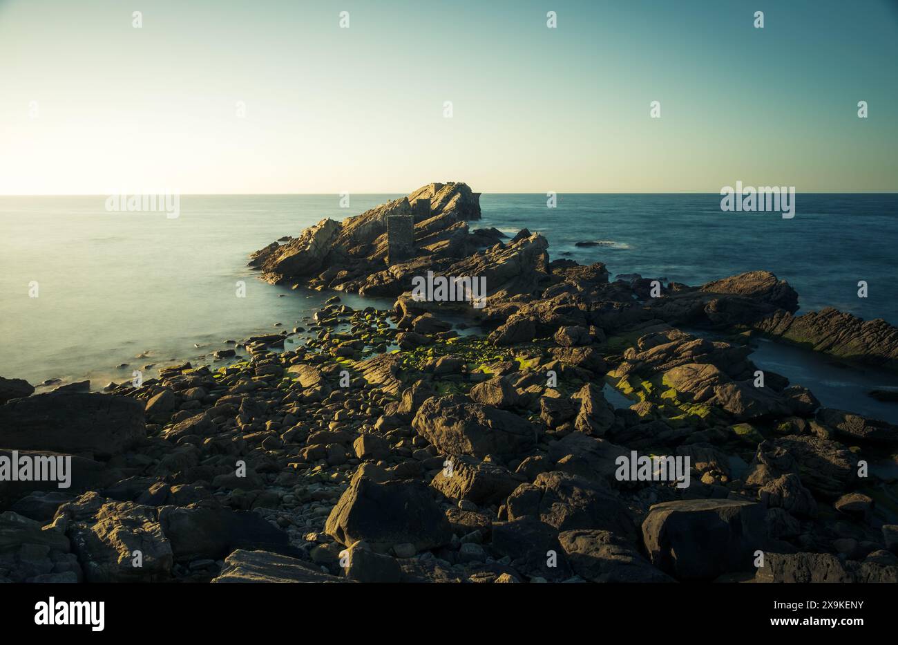 coastal landscape in which an old loading dock juts into the sea, long ...