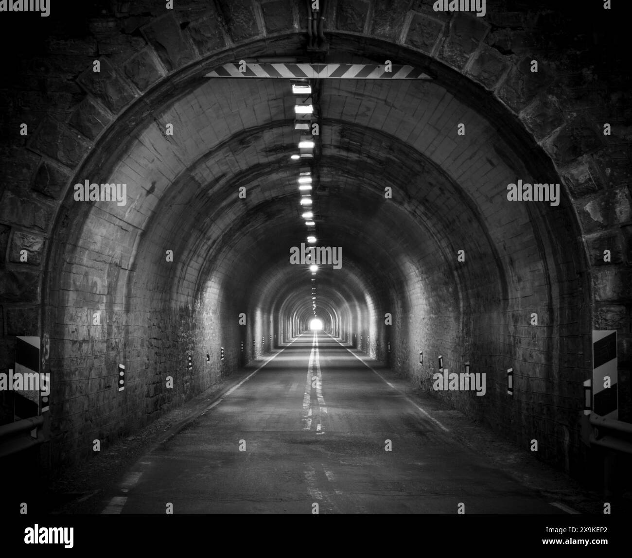 black and white photo of a long, straight tunnel with lights inside but ...