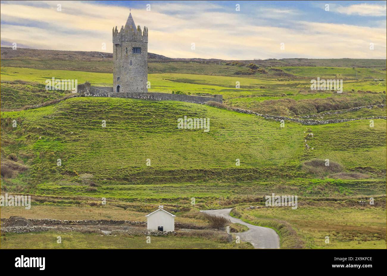 Ancient irish castle stood on a hill overlooking a small white cottage ...