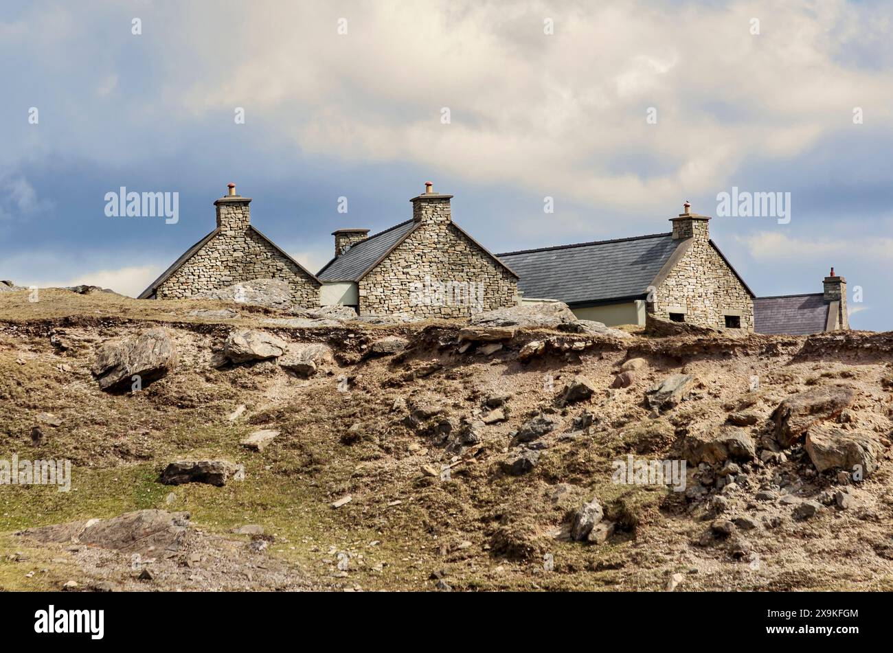 Looking upwards at a cliff face with houses ontop made of stone on ...