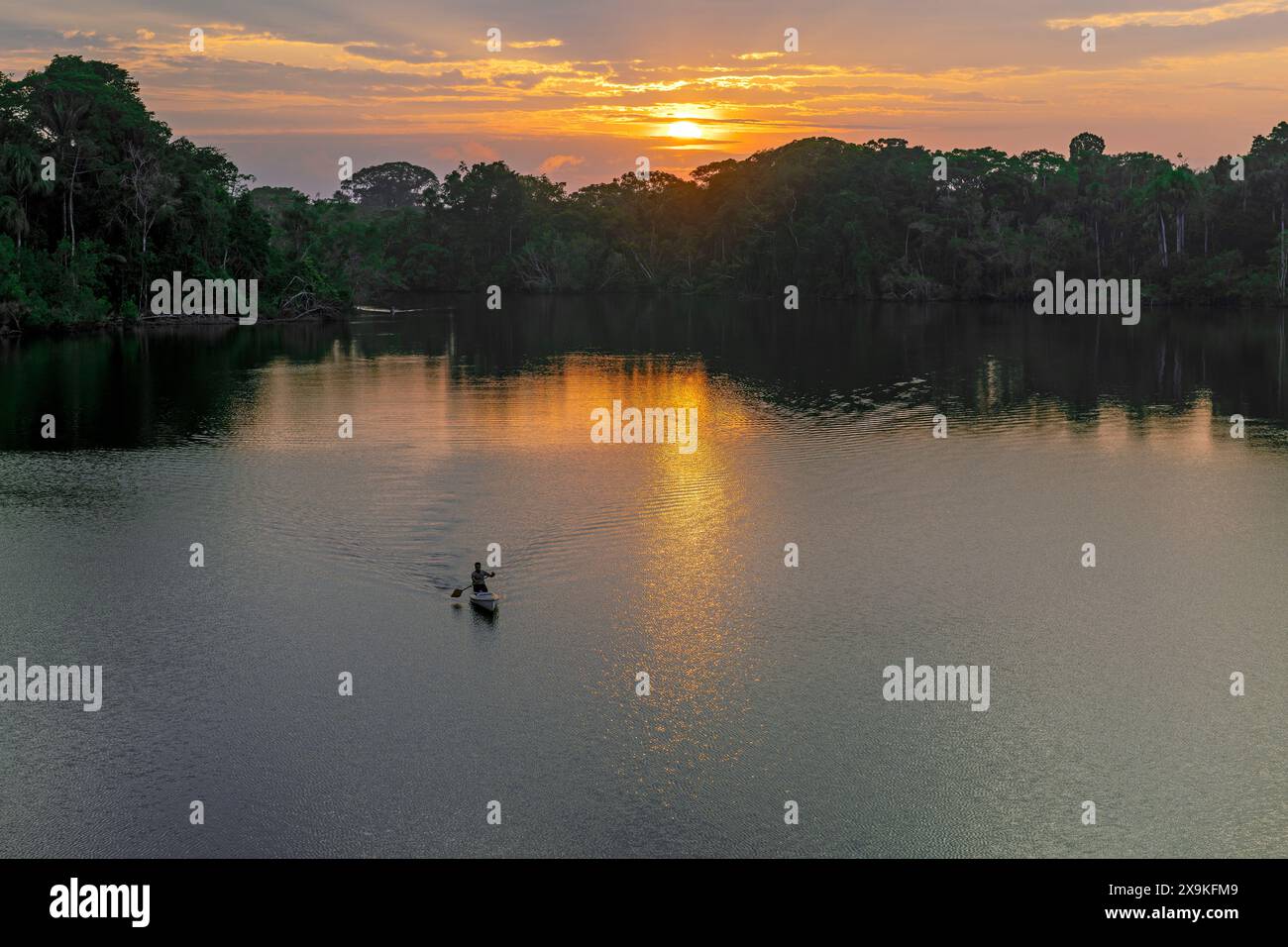 Indigenous Quechua man riding canoe at sunrise, Amazon Rainforest ...
