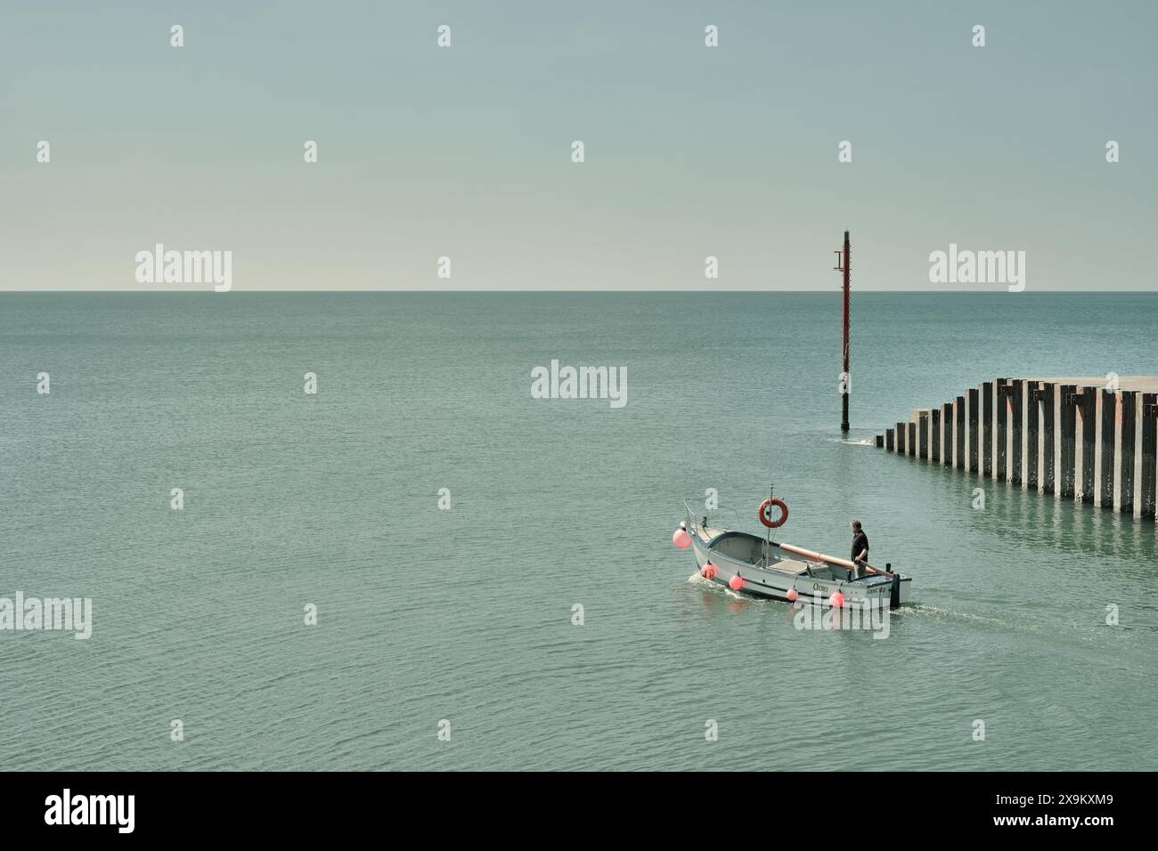 A fisherman guides a small fishing boat out of West Bay harbour in ...