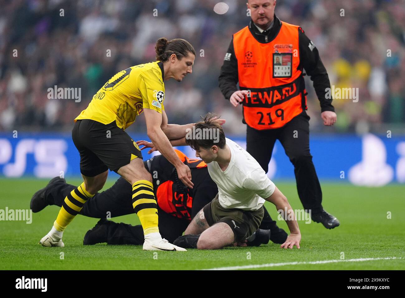 A pitch invader is tackled by Borussia Dortmund's Marcel Sabitzer and ...