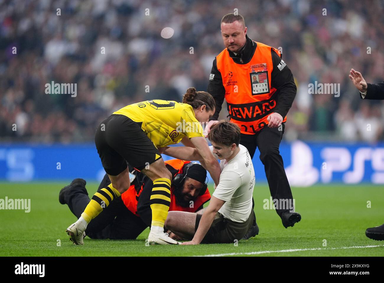 A pitch invader is tackled by Borussia Dortmund's Marcel Sabitzer and ...