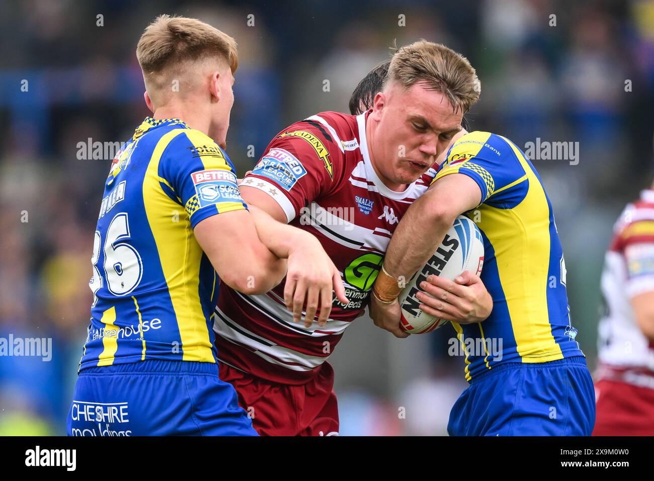 Harvie Hill of Wigan Warriors is tackled by Nolan Tupaea of Warrington ...