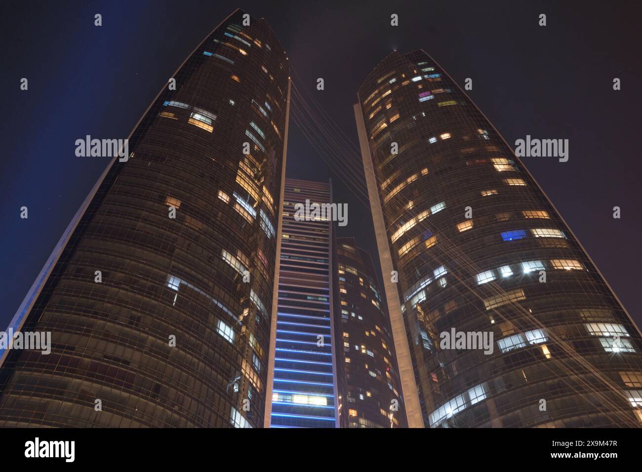 The Etihad Towers hotel in Abu Dhabi at night as seen from below ...