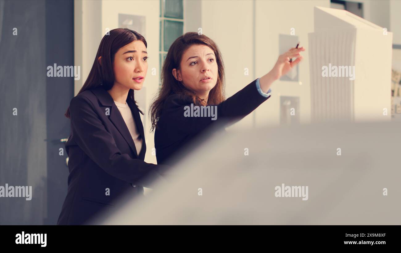 Industrial designers drawing lines on blueprints in agency office ...