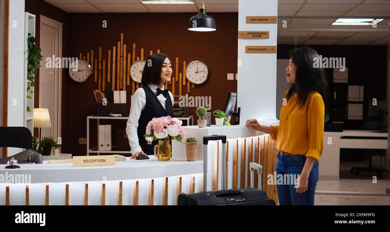 Receptionist welcoming asian woman at five star resort, asking about ...
