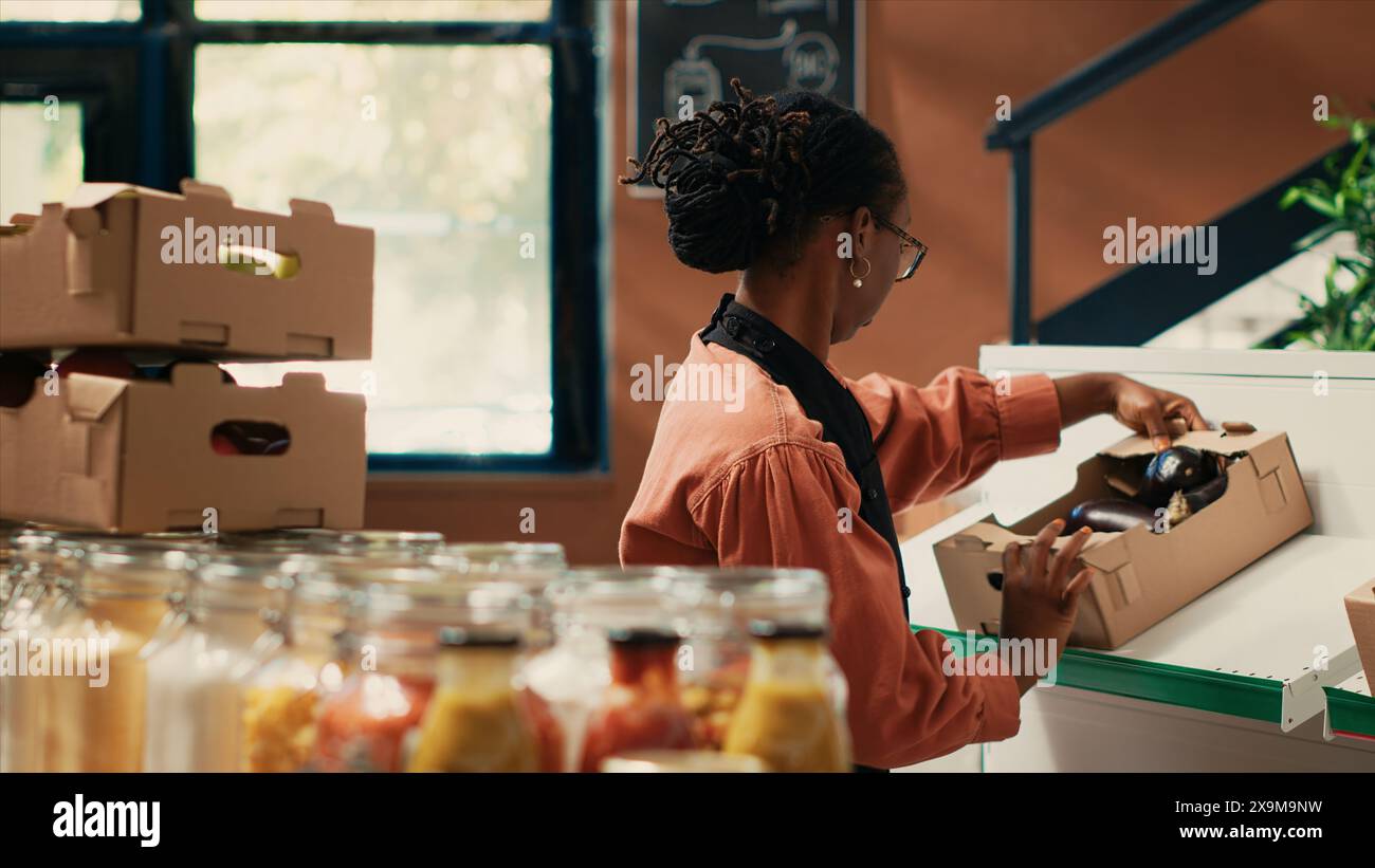 Merchant organizing fruits and veggies in crates on shelves, preparing ...