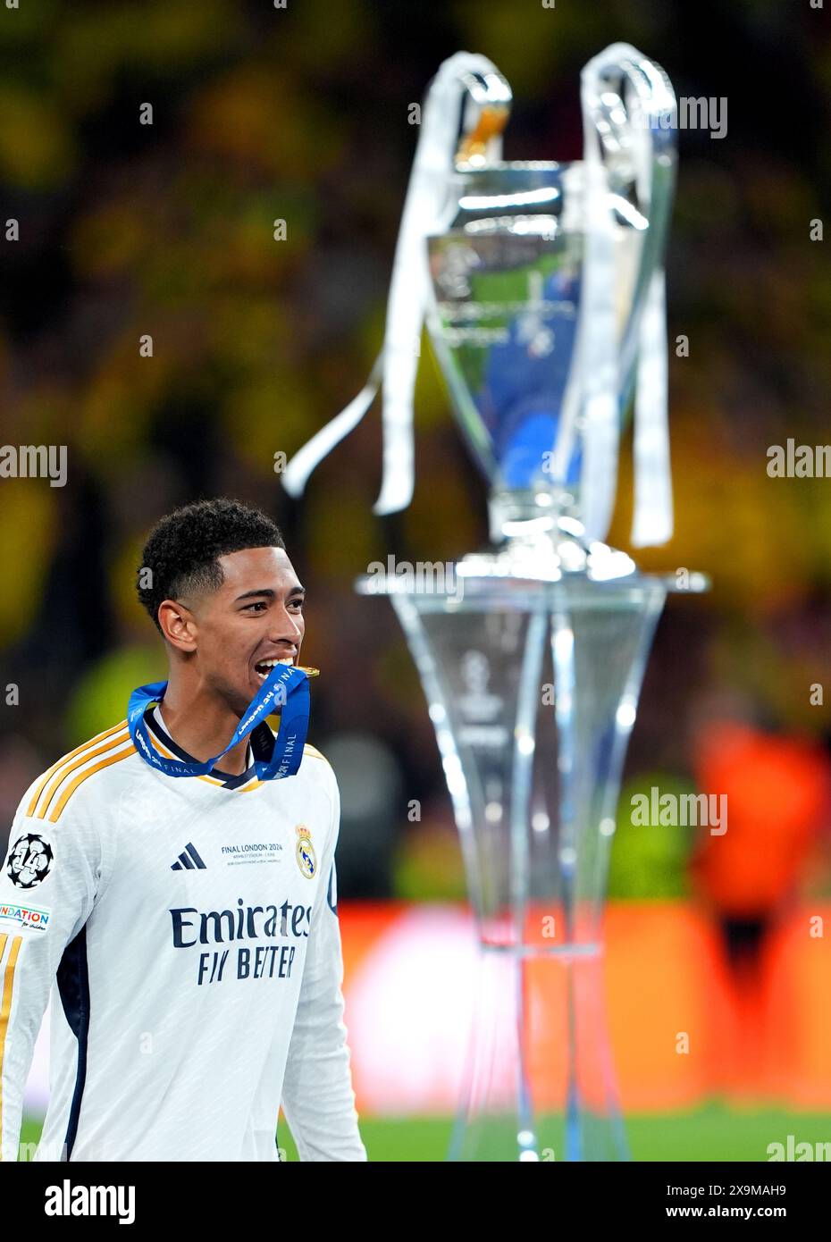 Real Madrid's Jude Bellingham bites his medal as he walks past the ...