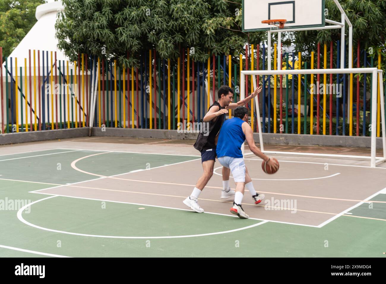 Two men playing basketball on an outdoor court Stock Photo - Alamy