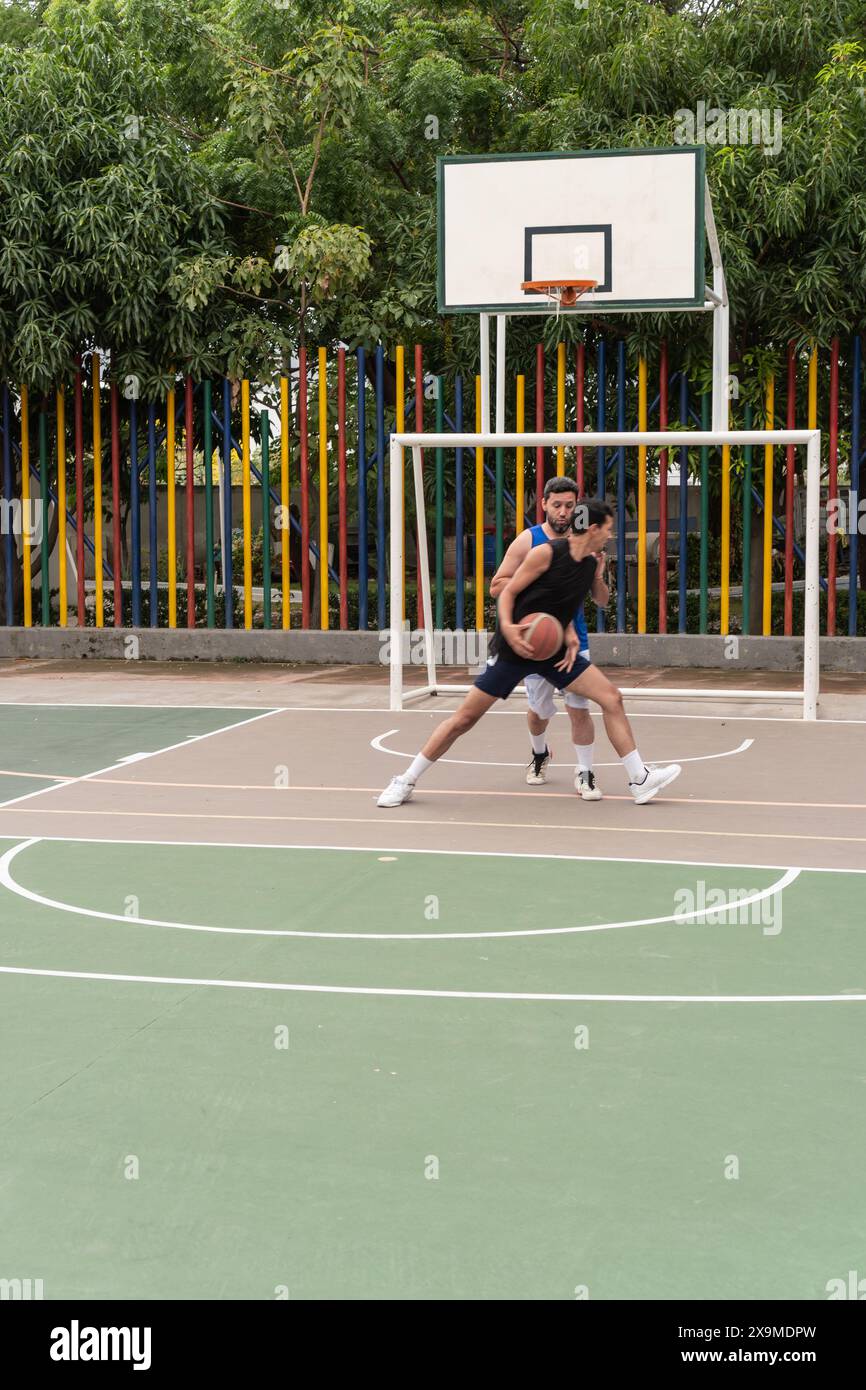 Two men competing in a basketball game on an outdoor court Stock Photo ...