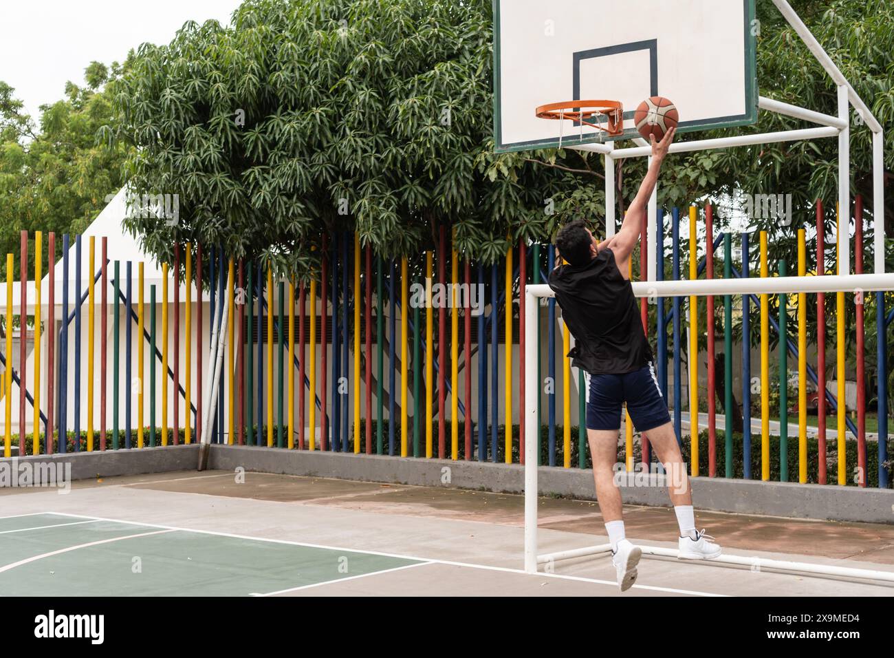 Man performing a dunk on an outdoor basketball court with colorful ...