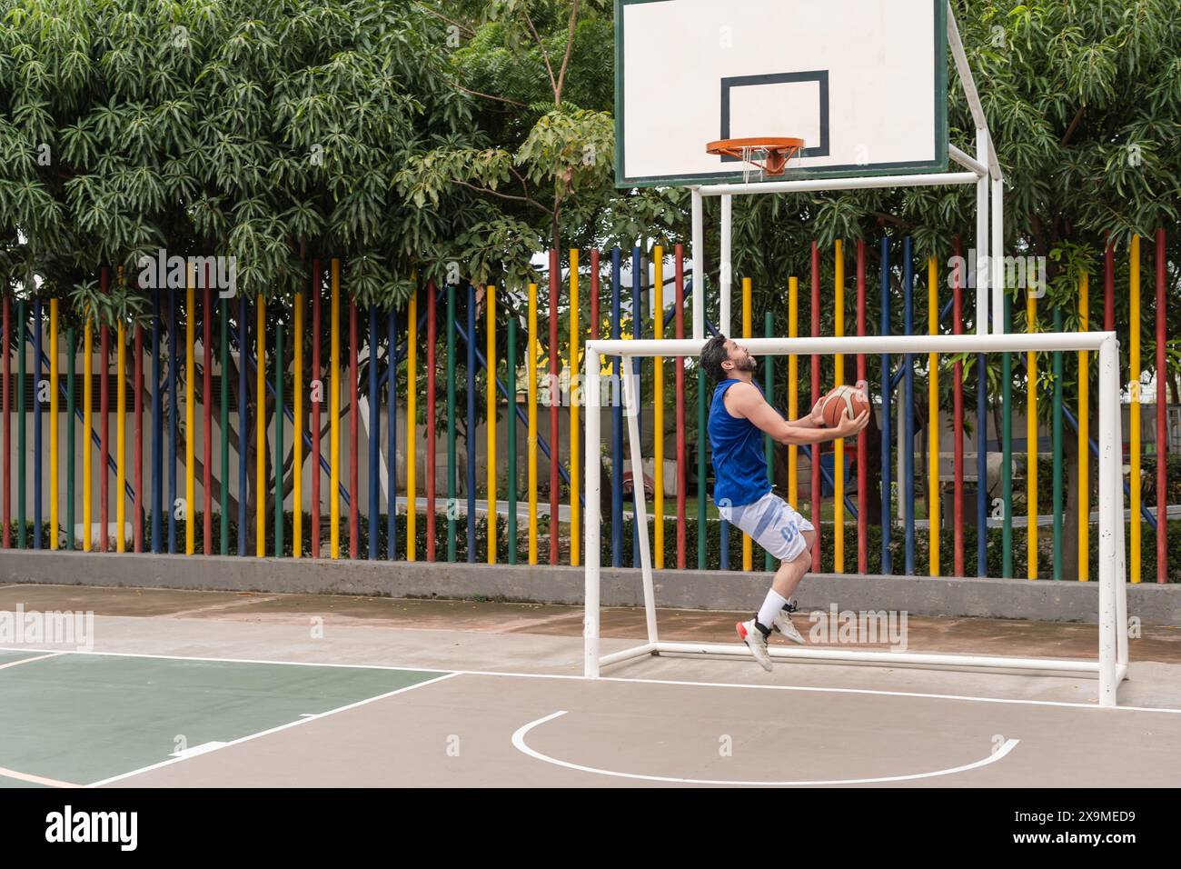 Man attempting a layup on an outdoor basketball court with colorful ...