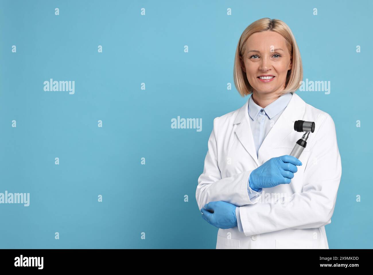 Happy dermatologist with dermatoscope on light blue background, space ...