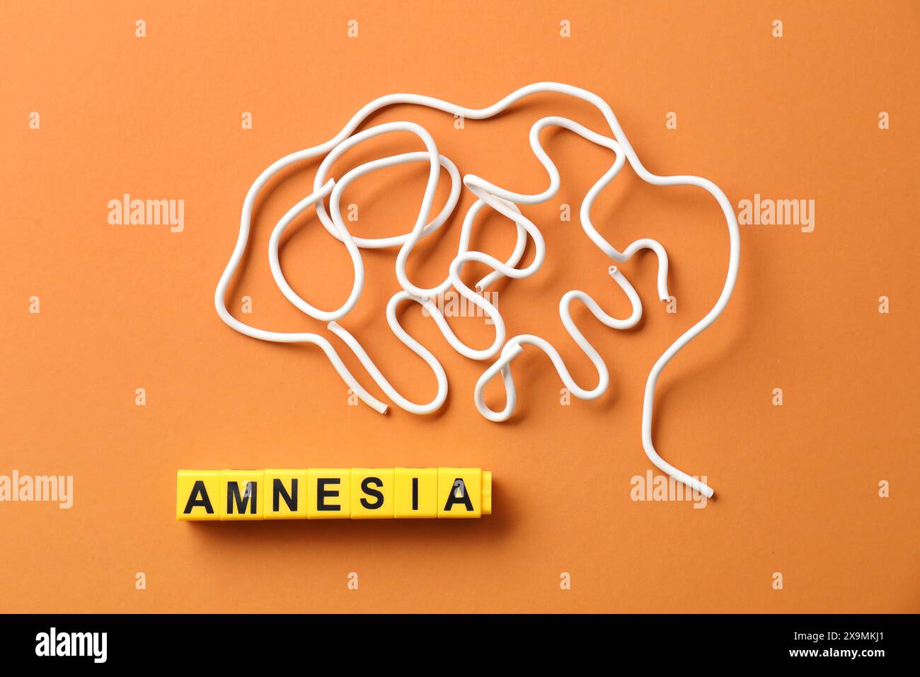 Word Amnesia and brain made of wires on orange background, flat lay ...