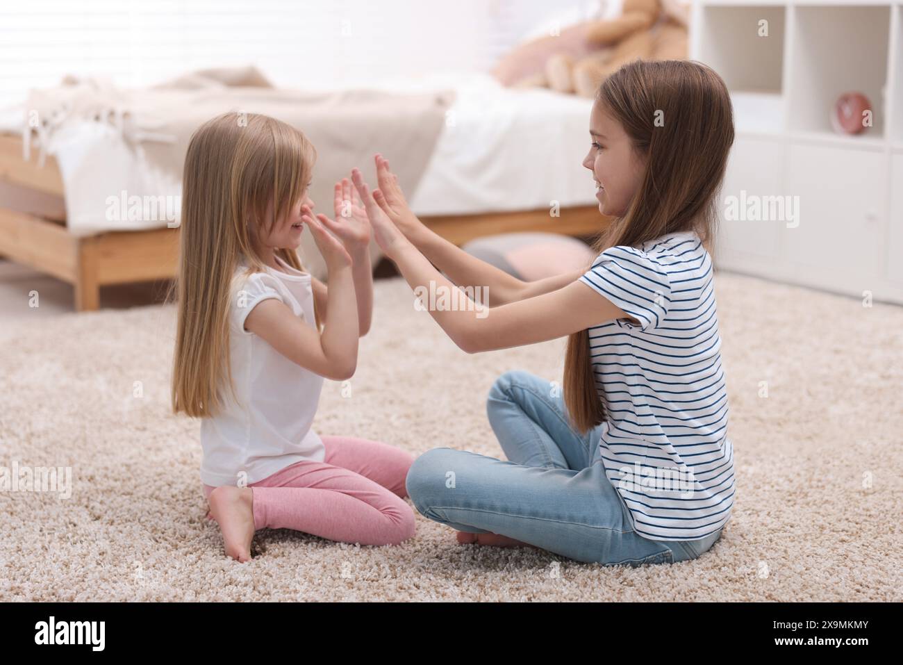 Cute little sisters playing clapping game with hands at home Stock ...