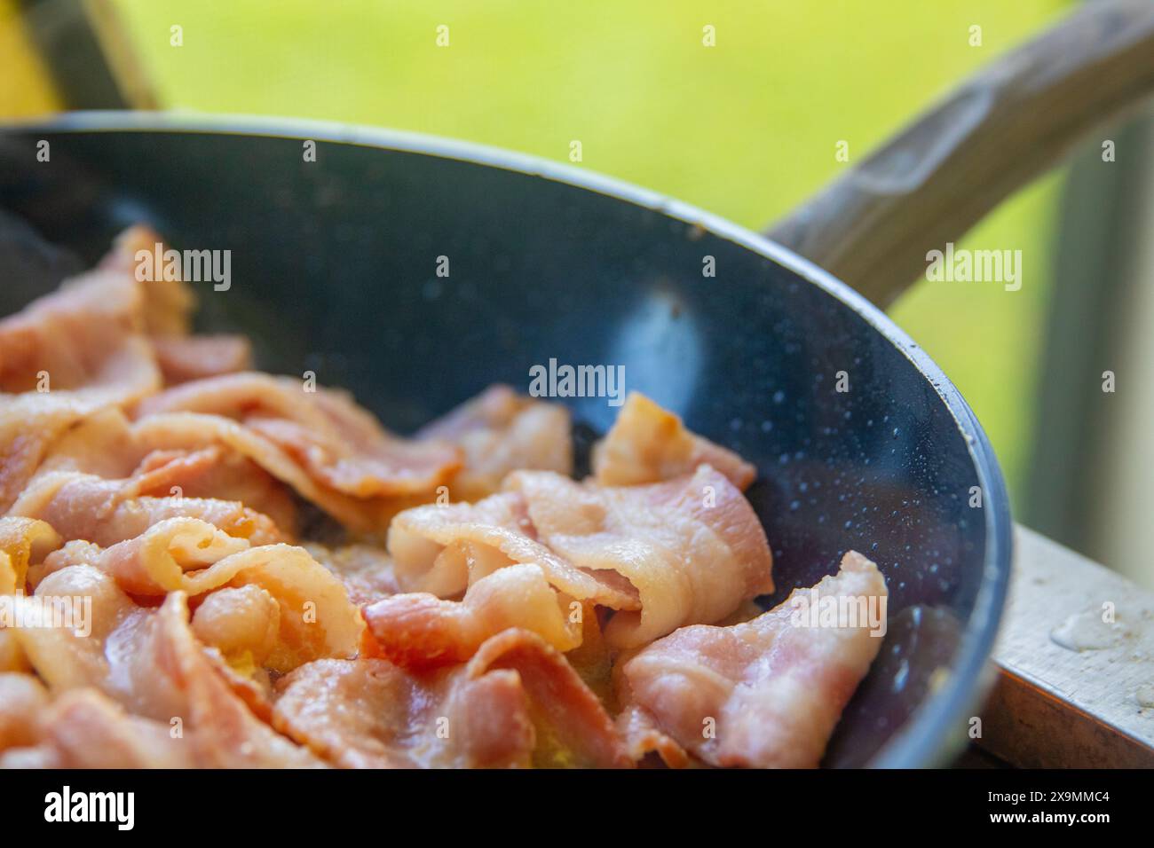Bacon sizzling in a pan outdoors Stock Photo - Alamy