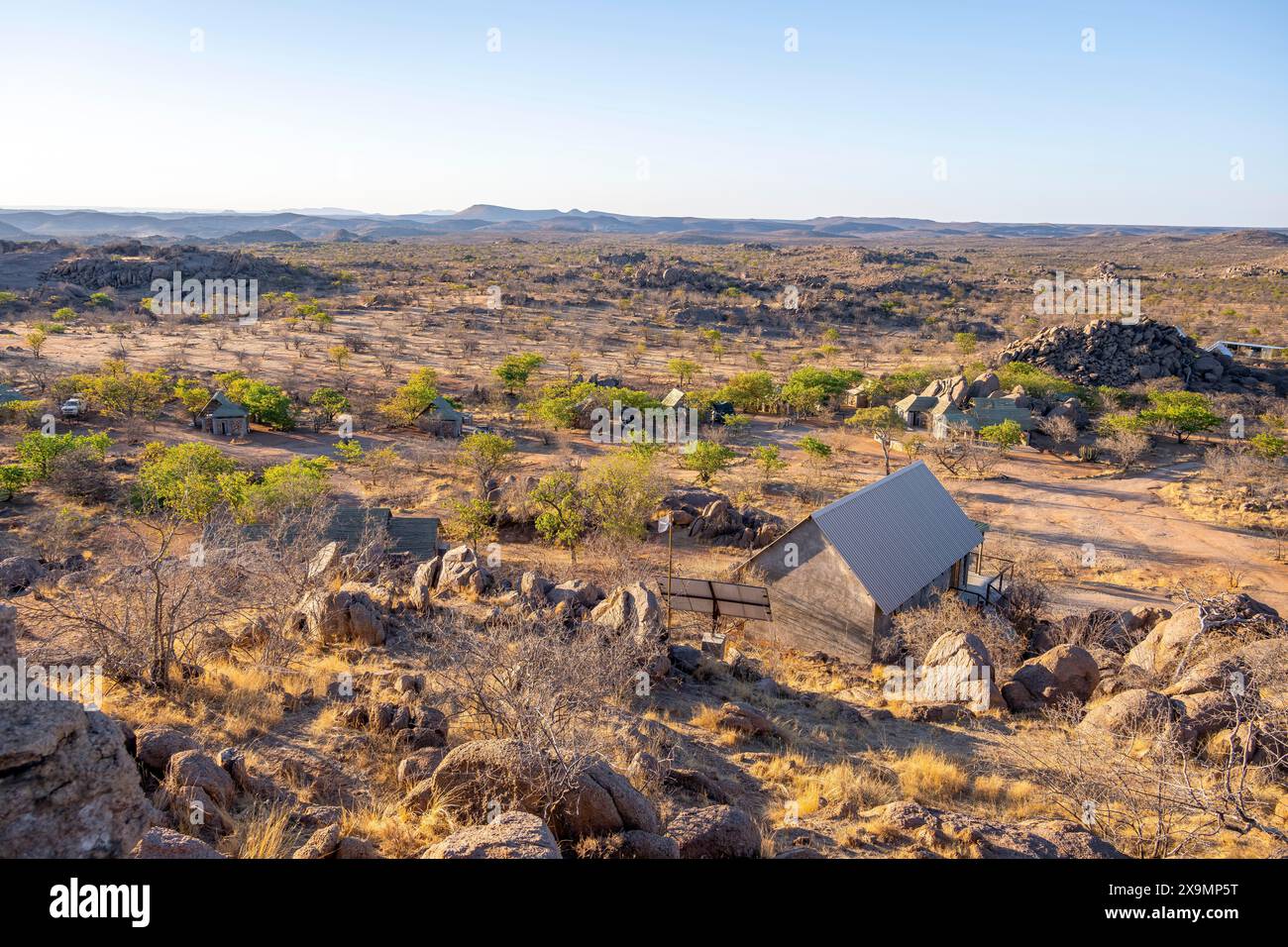 Hobatere Roadside Campsite, Barren landscape with rocky hills and acacia trees, African savannah ...