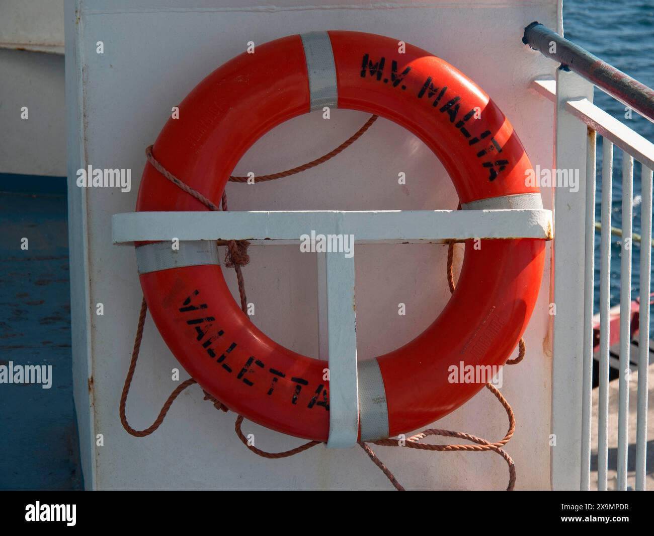 A bright orange lifebuoy with lettering on board a boat, the island of ...