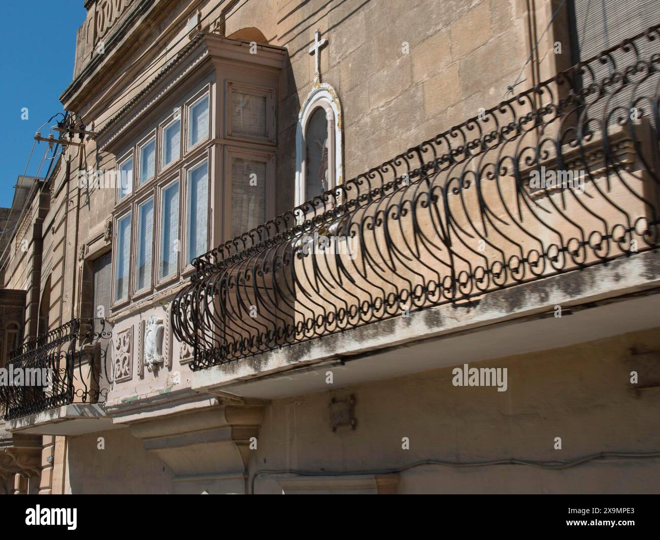 Facade of an old building with wrought iron balcony railings and a ...